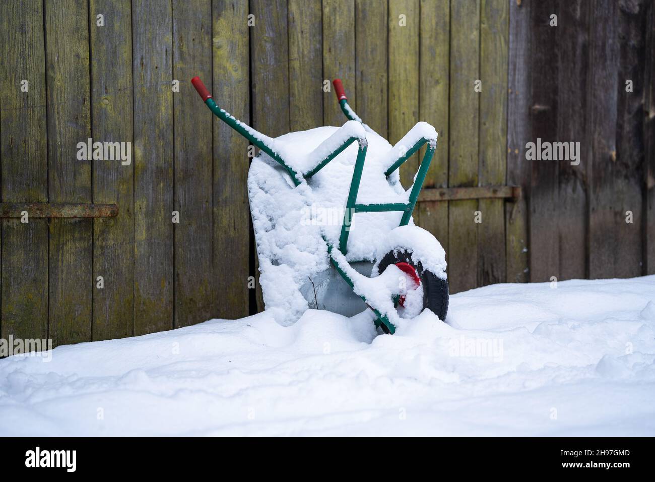 Wheelbarrow at a wall in snow at winter time Stock Photo - Alamy