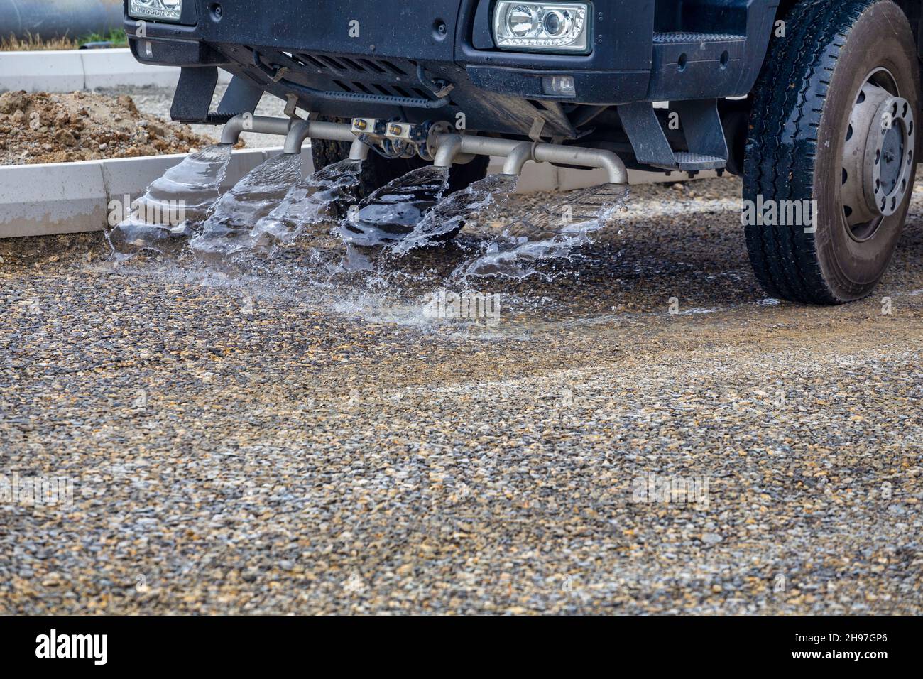 Water truck spraying a newly graded road and prepare for asphalting ...