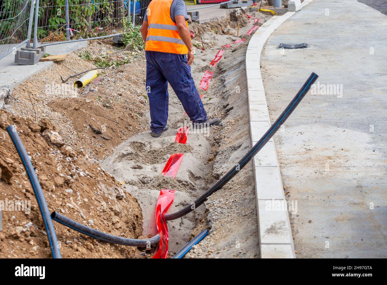 Worker placing warning tape in the trench to identify a cable duct ...