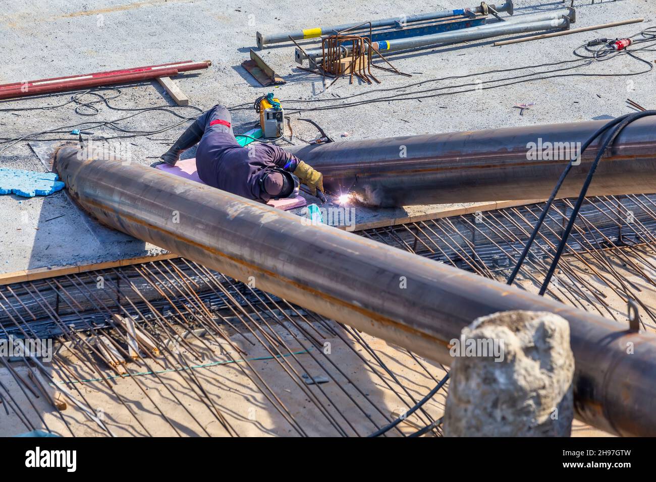 Worker welding metal pole construction for slope protection at ...