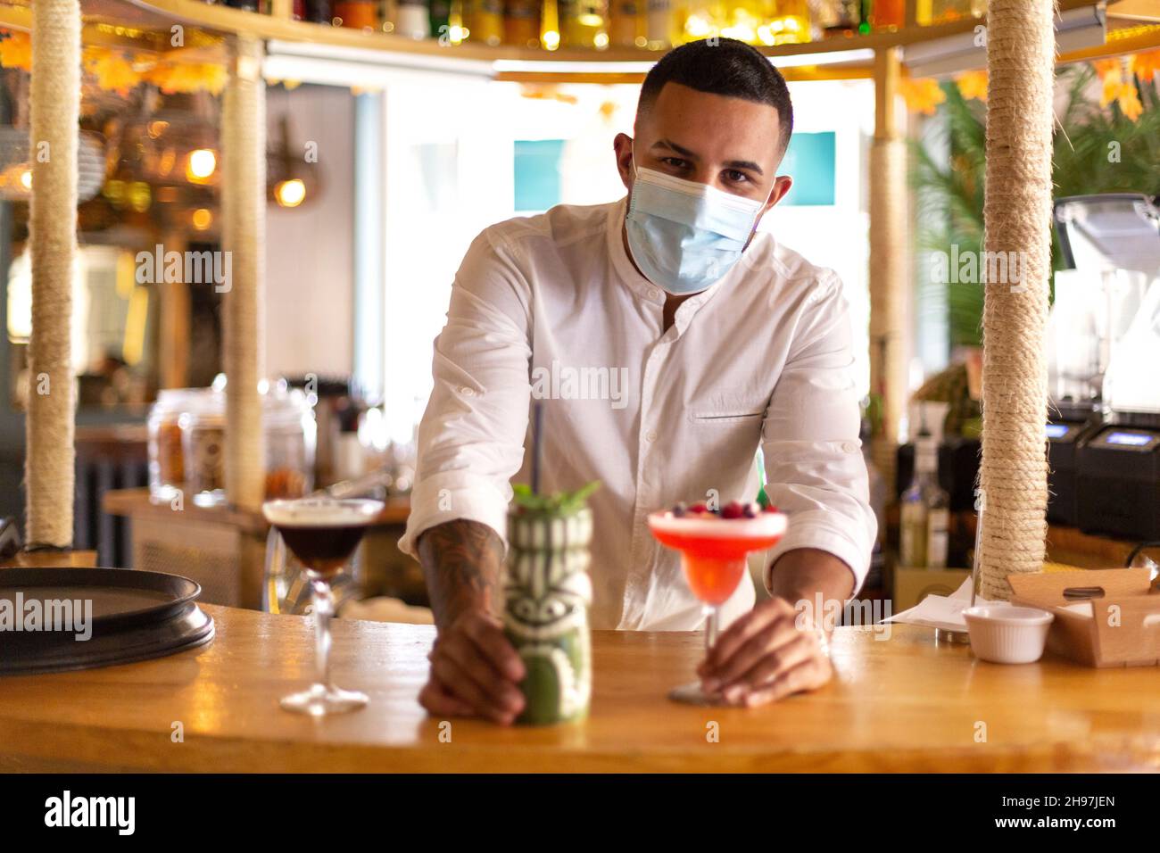 Elegant young Latin American bartender serving a cocktail at the bar of ...