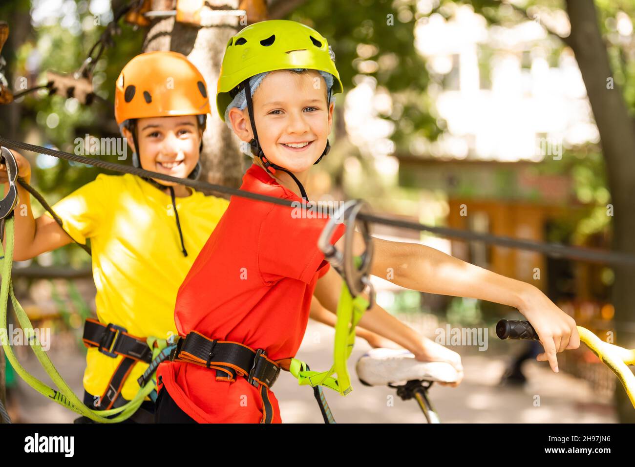Child in forest adventure park. Kids climb on high rope trail. Agility ...