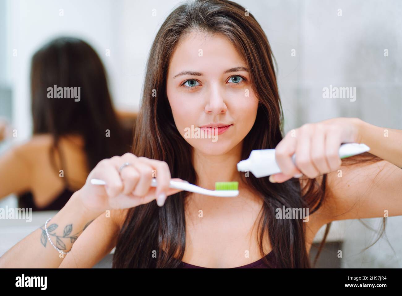 Close is portrait of young woman holding toothpaste and a toothbrush ...