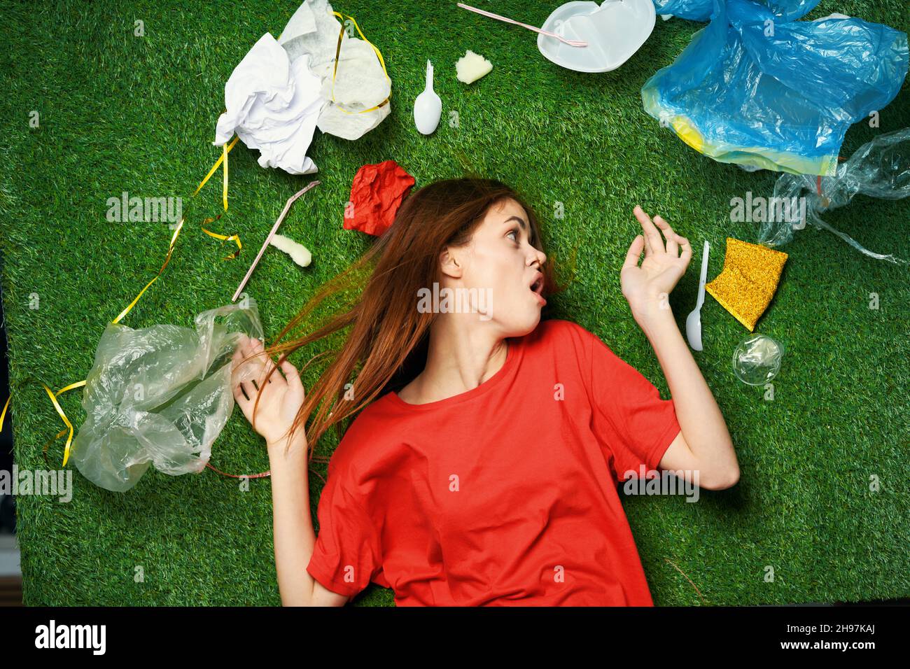 woman lying on the lawn plastic trash ecology pollution Stock Photo - Alamy