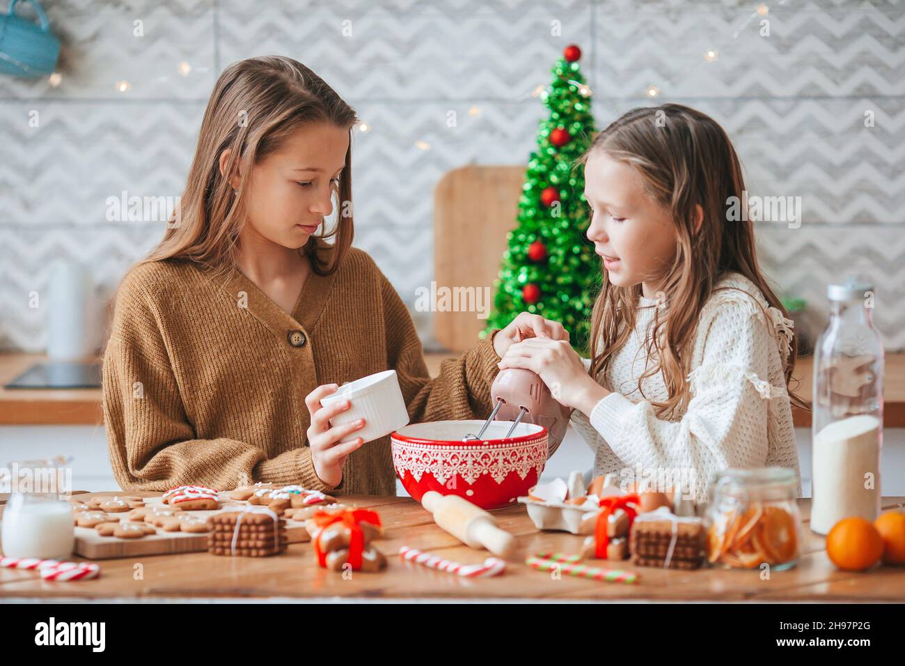 Adorable little girls baking cookies background of lights and Christmas ...