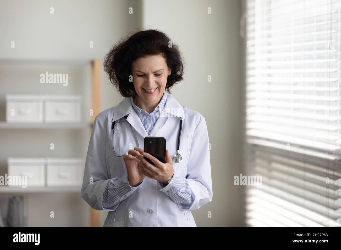 Happy senior GP doctor chatting on mobile phone Stock Photo - Alamy