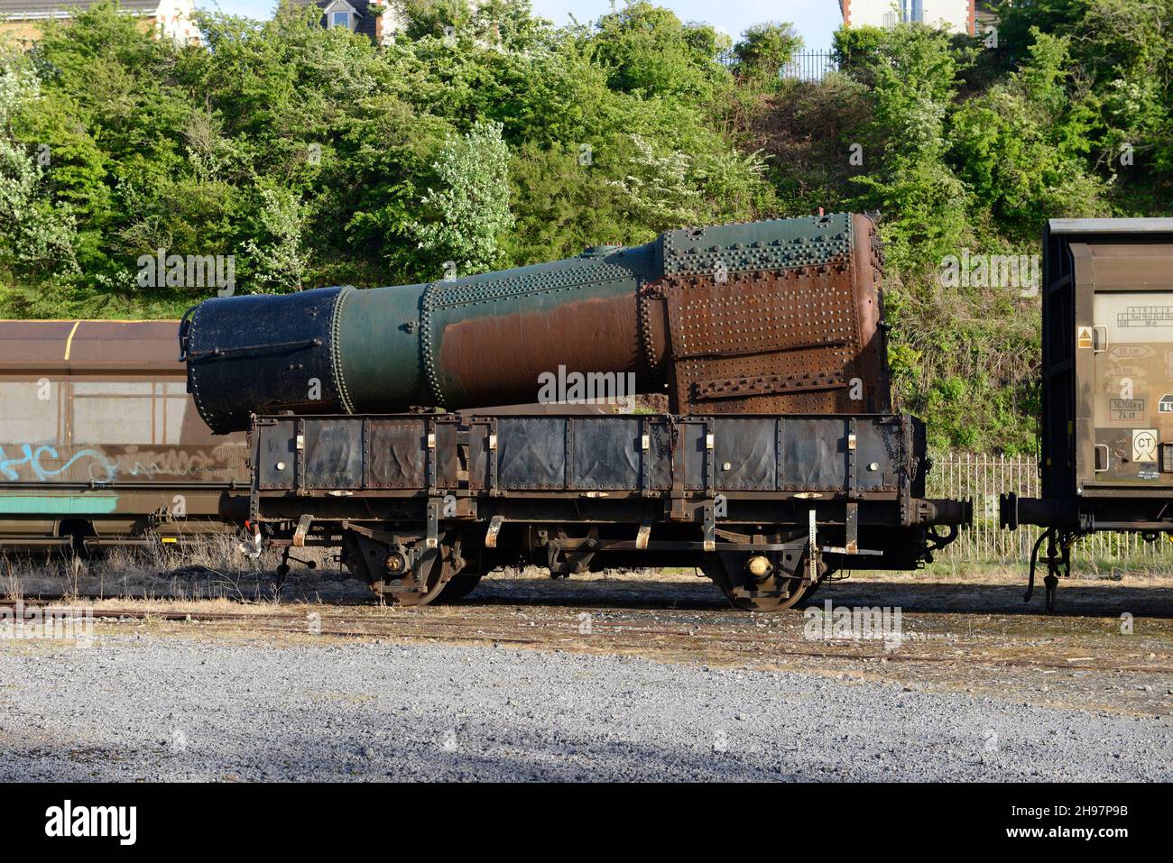 The boiler of a preserved steam locomotive sits on a wagon in sidings ...