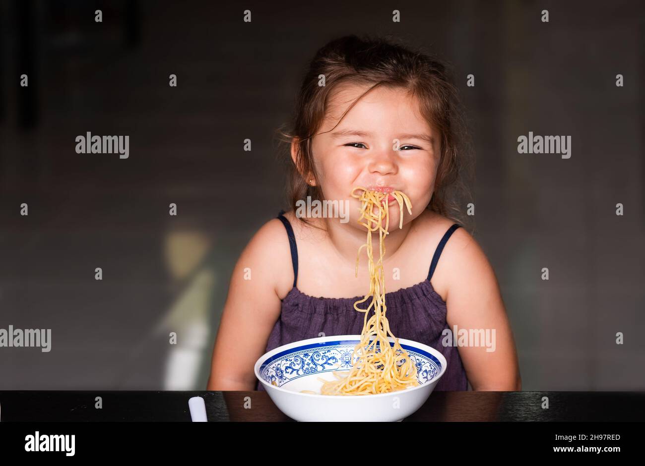 Cute child girl eating spaghetti and smiling Stock Photo - Alamy