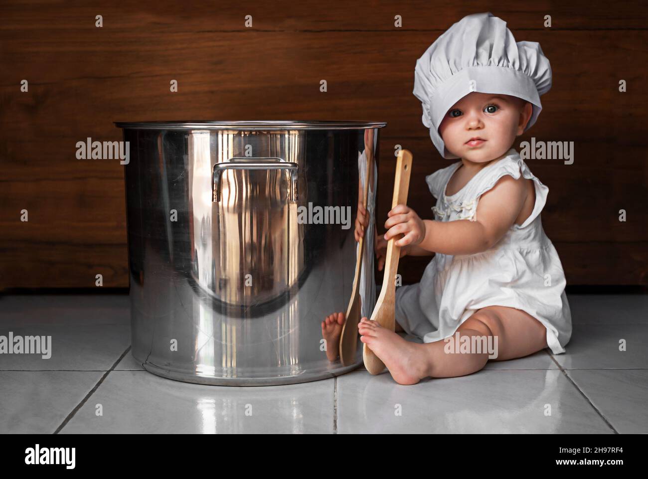 cute baby in the chef hat with a spoon and the large saucepan Stock ...