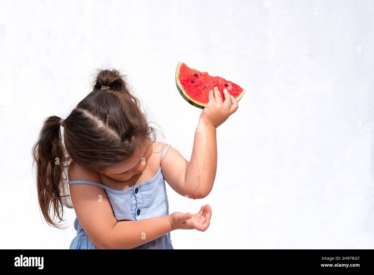Cute child catches the juice of red watermelon, which flows down the ...