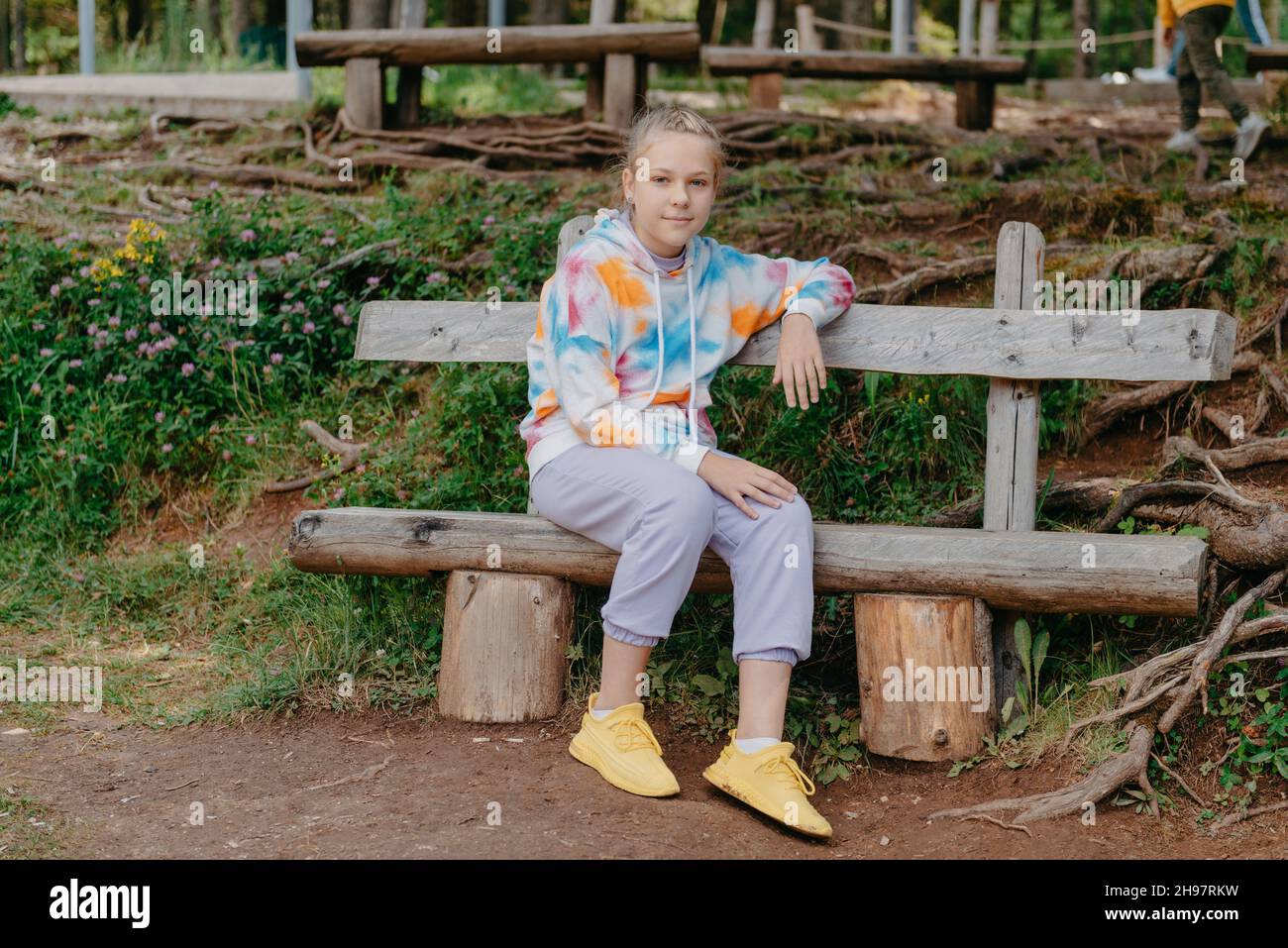 Cute teenage girl sitting on a wooden bench in the park. Cute teenage ...