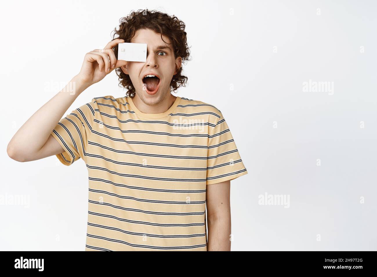 Enthusiastic handsome guy showing credit card, gasping amazed, standing ...