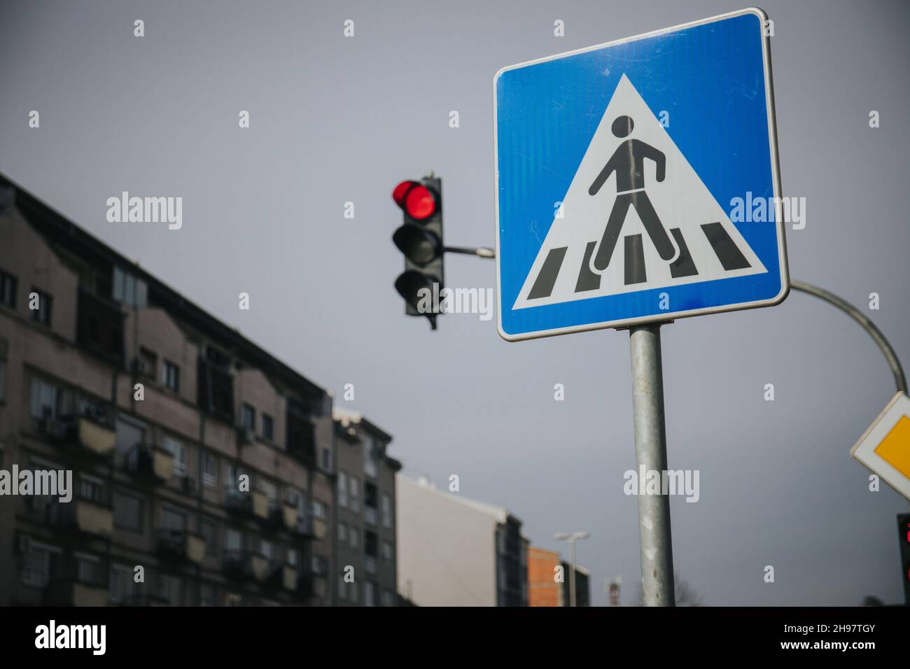 A low angle shot of a pedestrian cross sign and red traffic lights in a ...