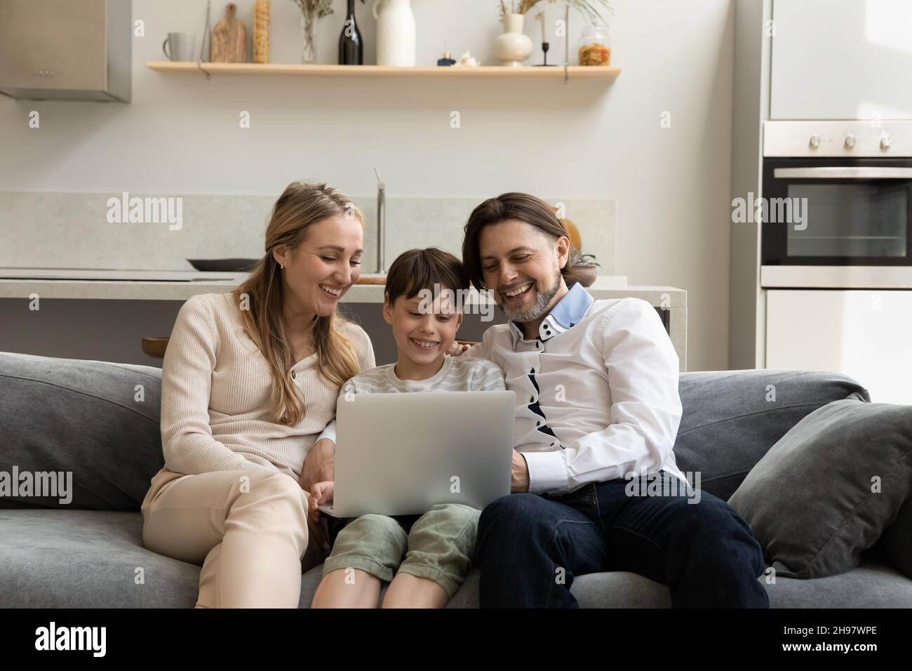 Happy adolescent boy using computer with couple parents Stock Photo - Alamy