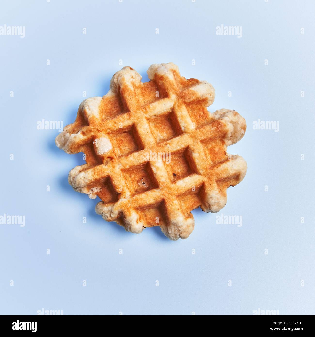 Single delicious waffle over blue background Stock Photo - Alamy