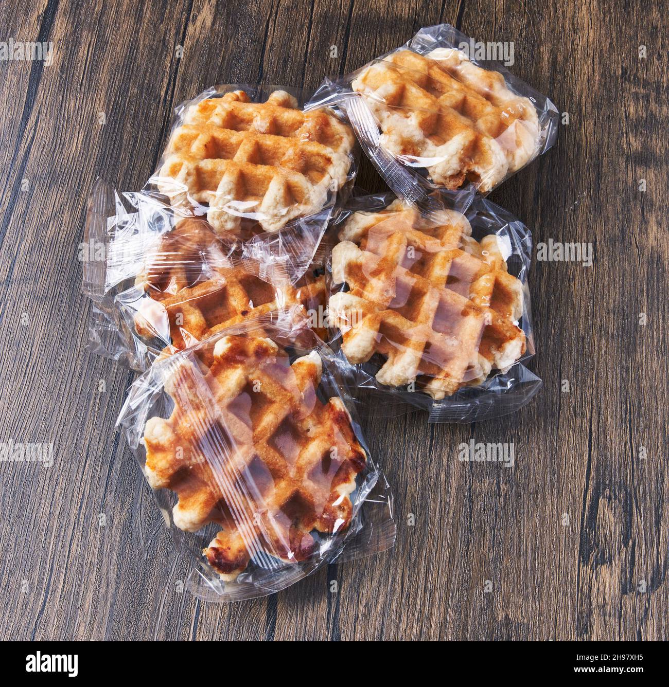 Bunch of delicious waffles wrapped on plastic bags on wooden surface ...