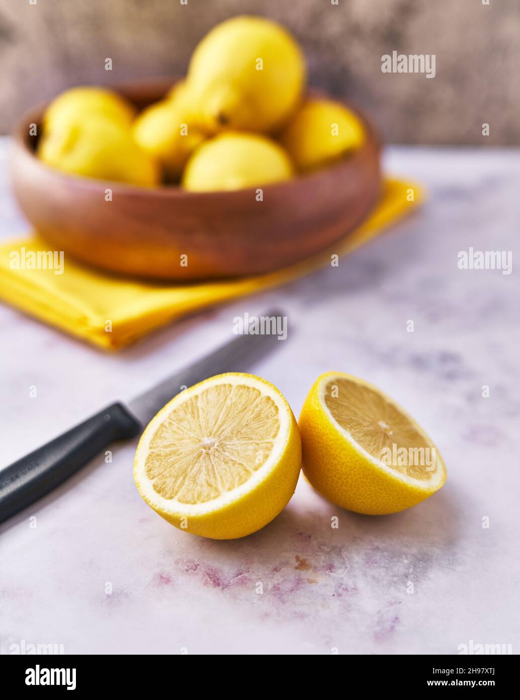 Bowl of bunch of lemons and halves on a marble surface Stock Photo - Alamy