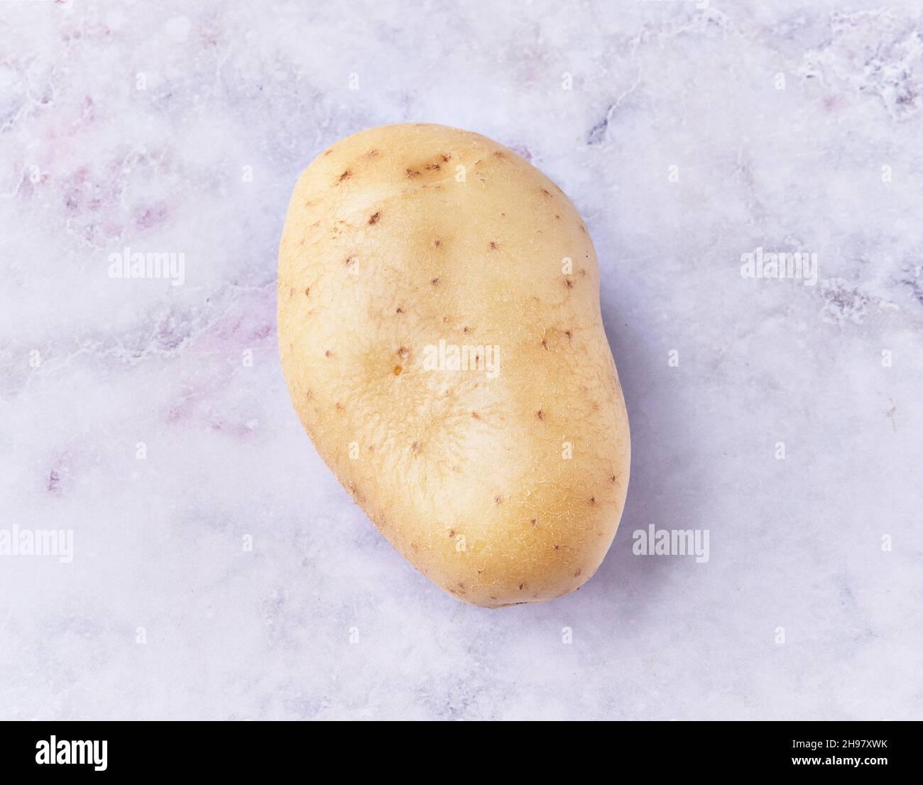 SIngle potato on a marble surface Stock Photo - Alamy