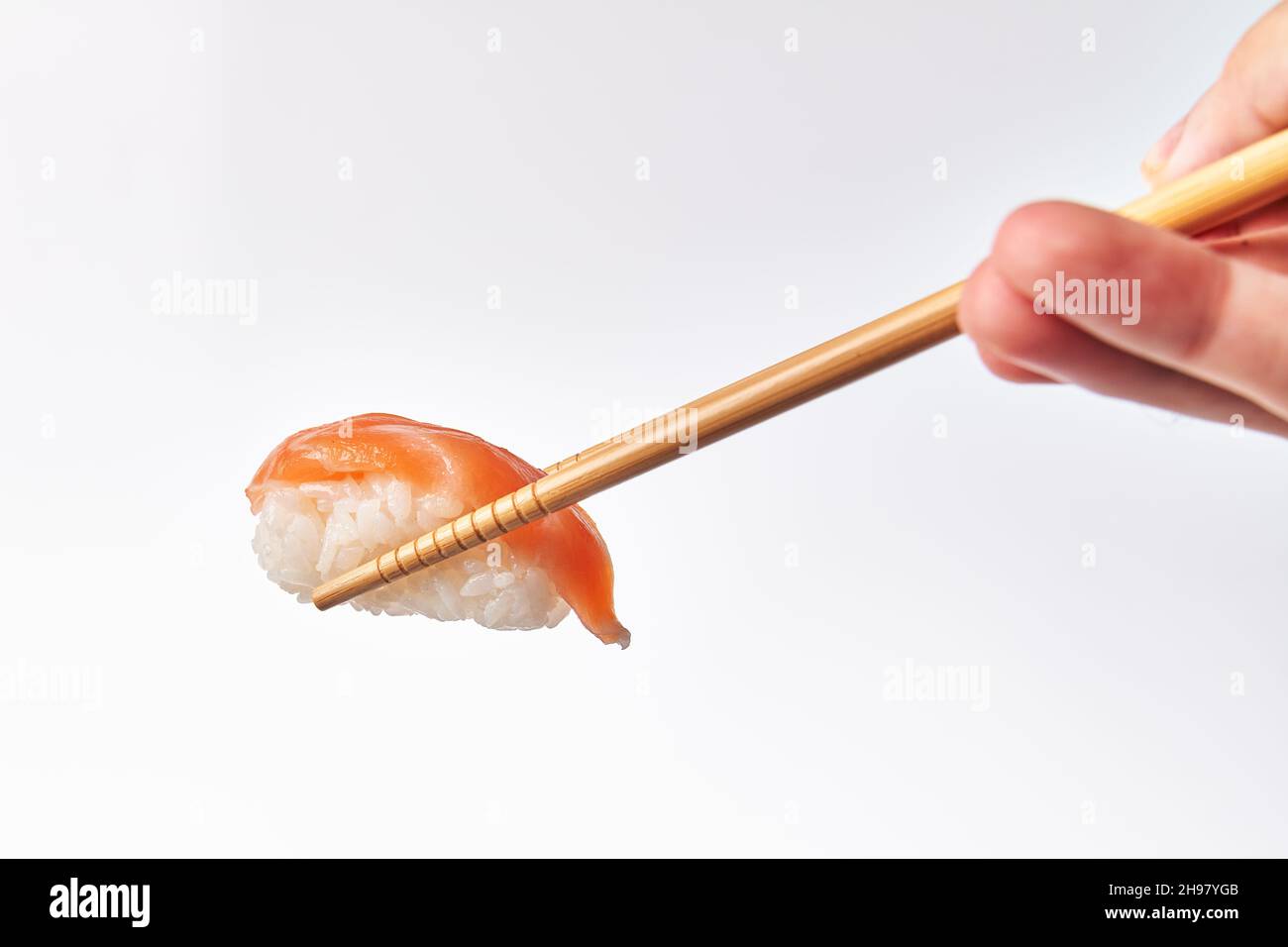 Chopsticks holding single salmon nigiri sushi isolated on white ...