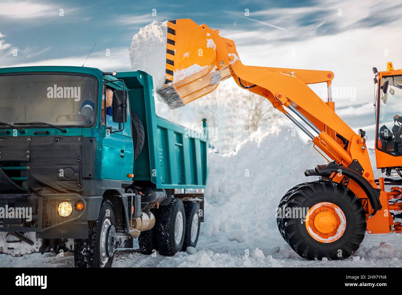 Snow removal after snowfall and blizzards. Excavator loads snow into ...