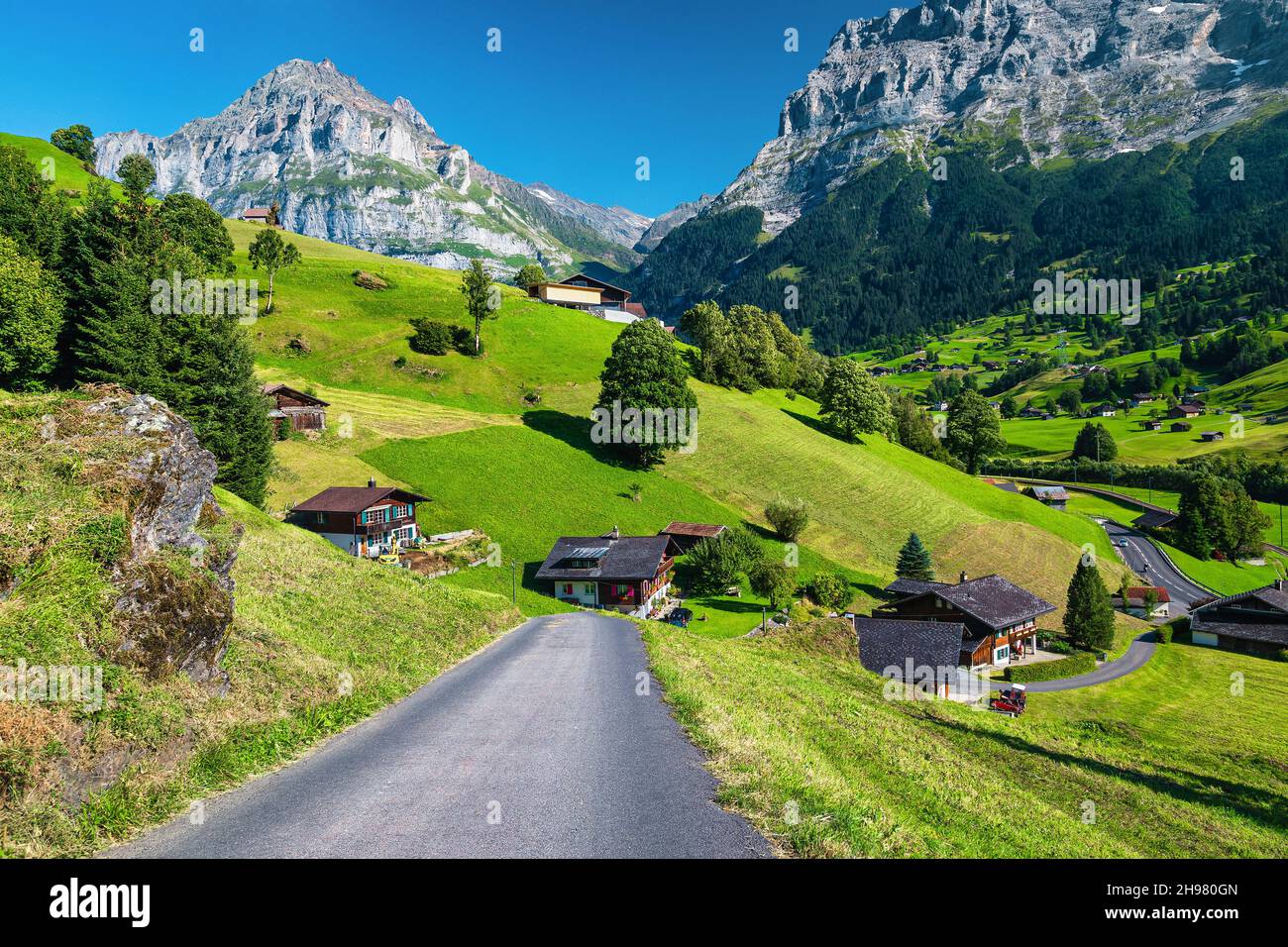 Famous alpine village with green meadows and farmlands on the slopes ...