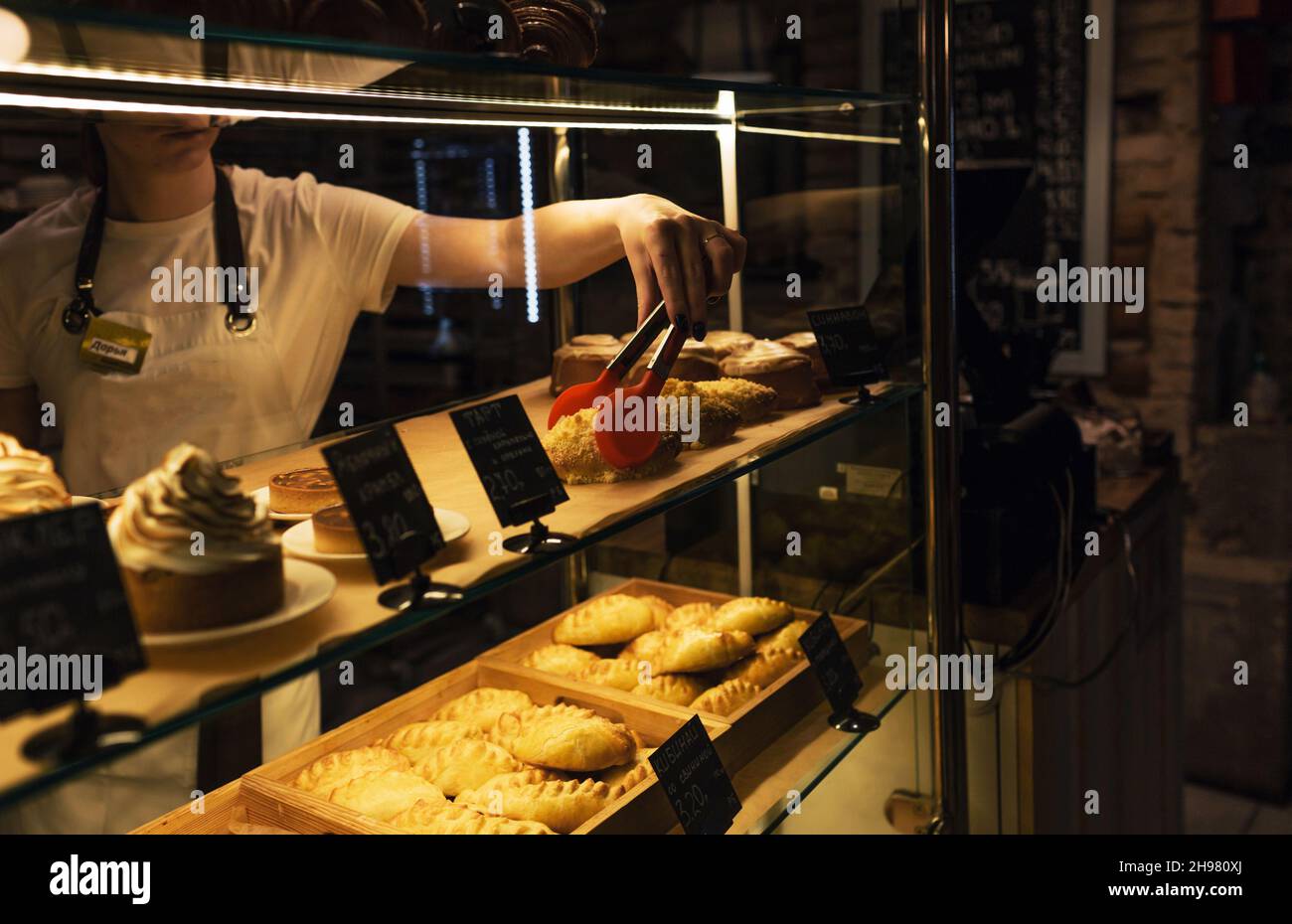 Panel. A woman working in a cafeteria puts delicious buns on public ...