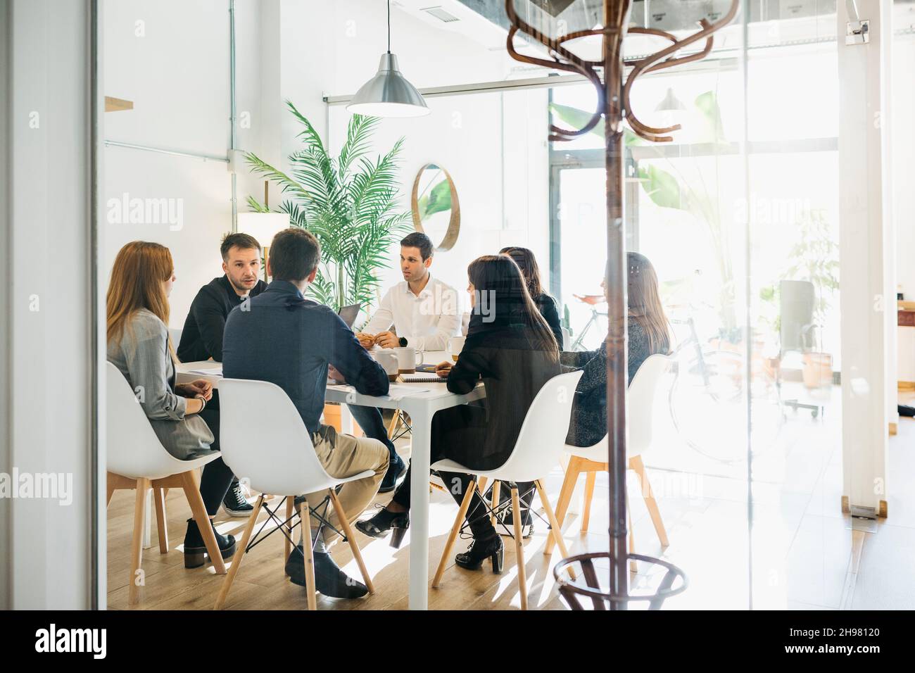 Business colleagues sitting at conference table, seen through glass ...