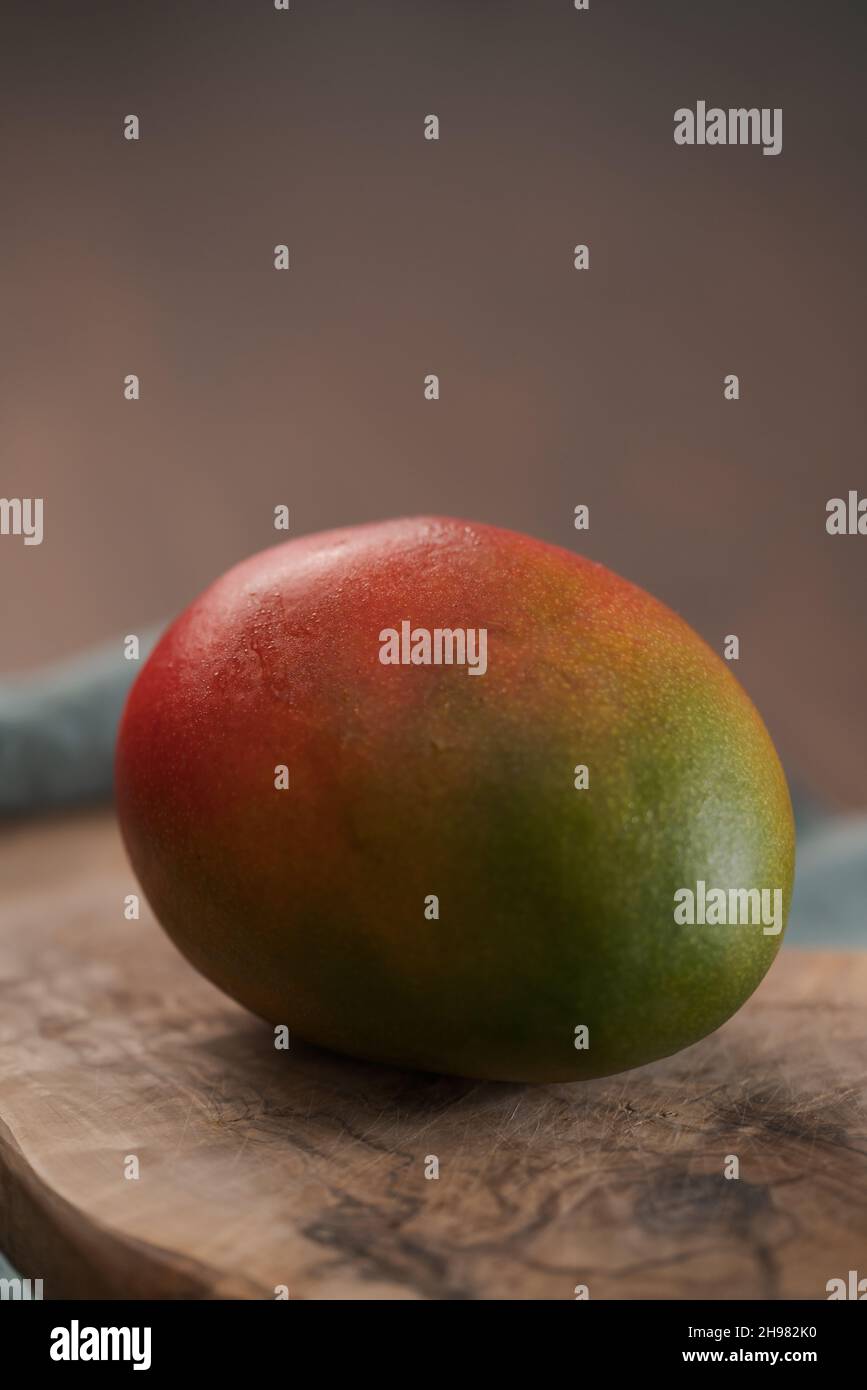 Whole ripe red mango on olive wood board, shallow focus Stock Photo - Alamy