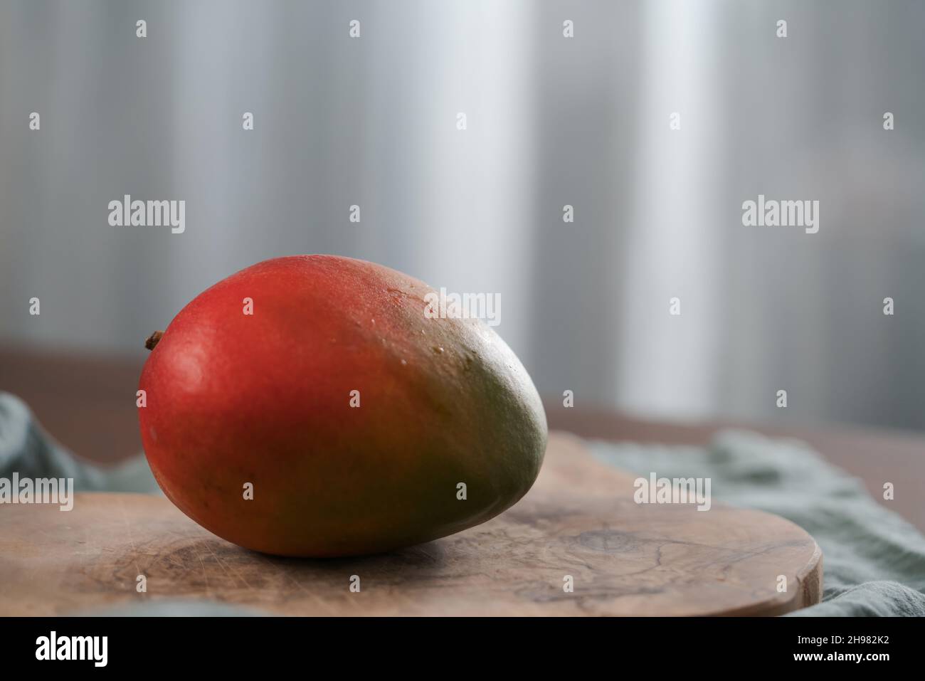 Whole ripe red mango on olive wood board, shallow focus Stock Photo - Alamy