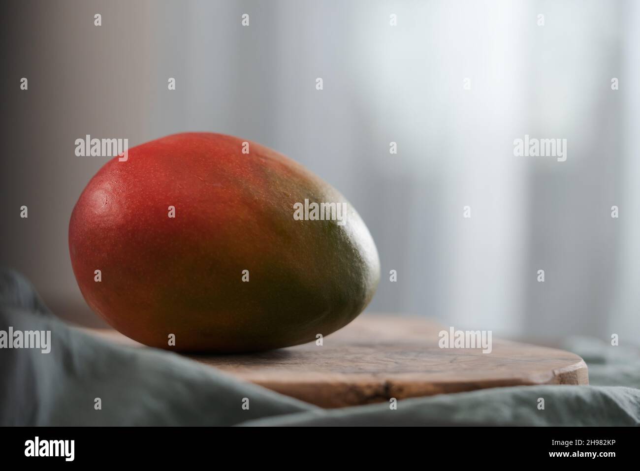 Whole ripe red mango on olive wood board, shallow focus Stock Photo - Alamy