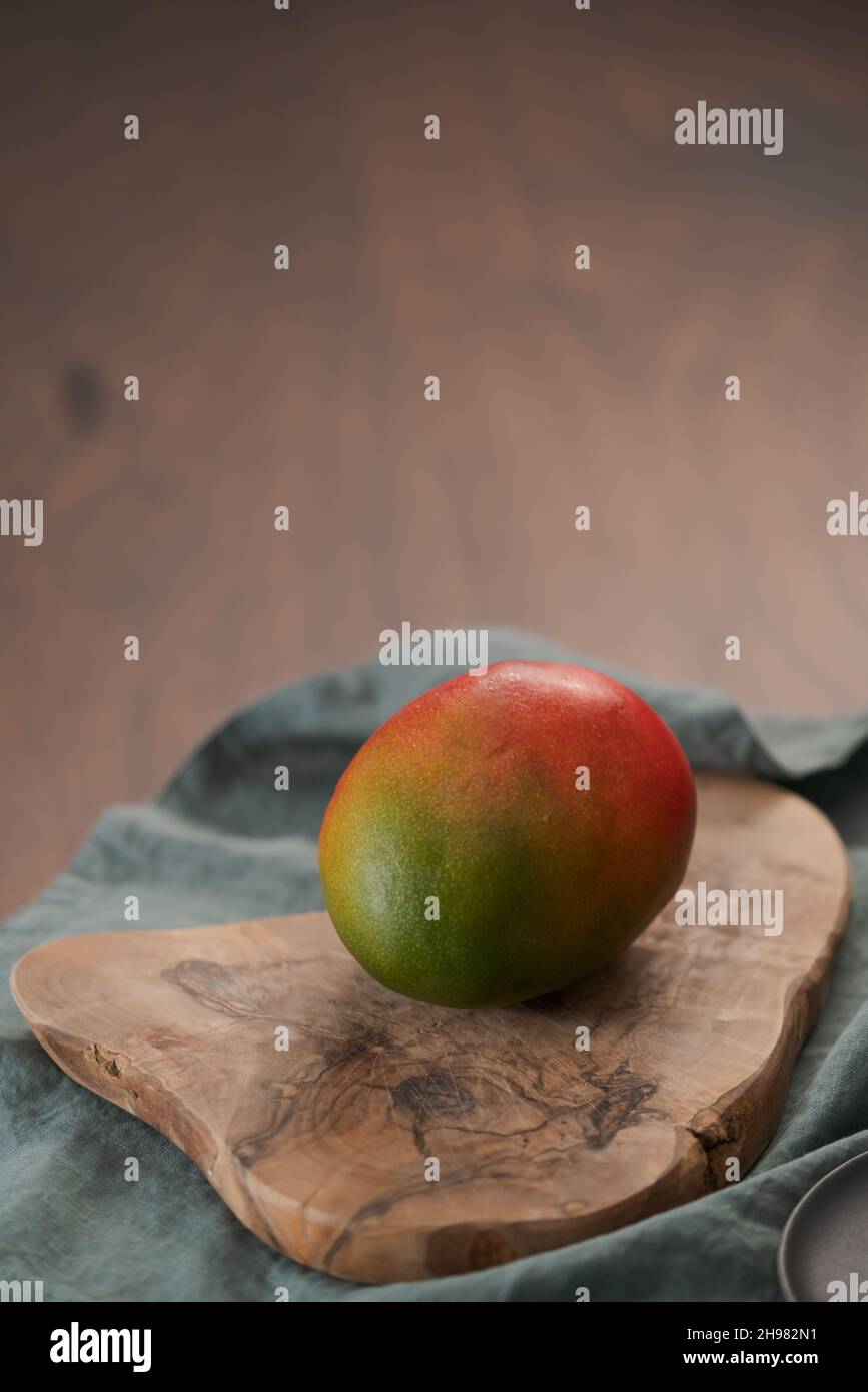 Whole ripe red mango on olive wood board, shallow focus Stock Photo - Alamy
