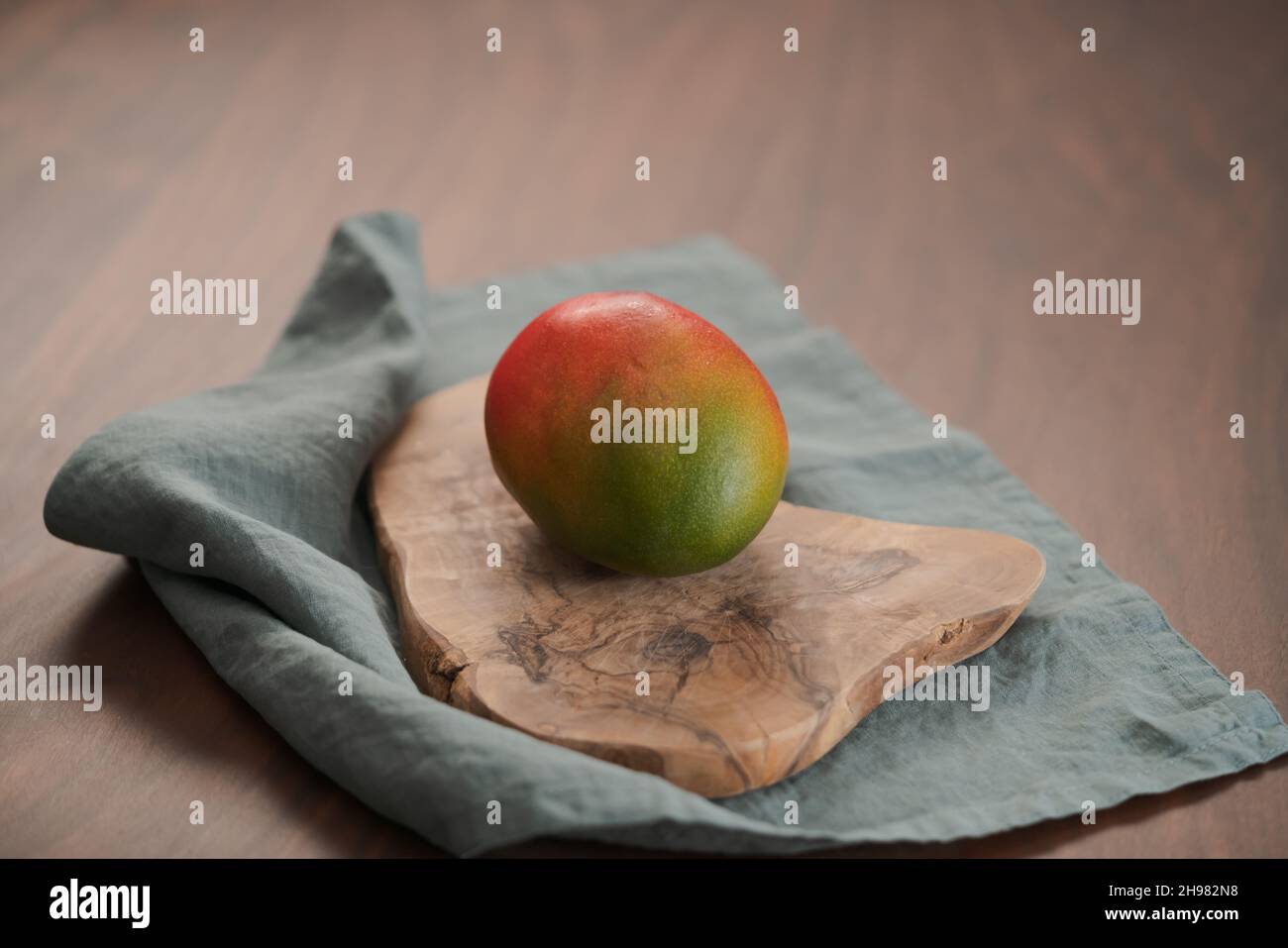 Whole ripe red mango on olive wood board, shallow focus Stock Photo - Alamy