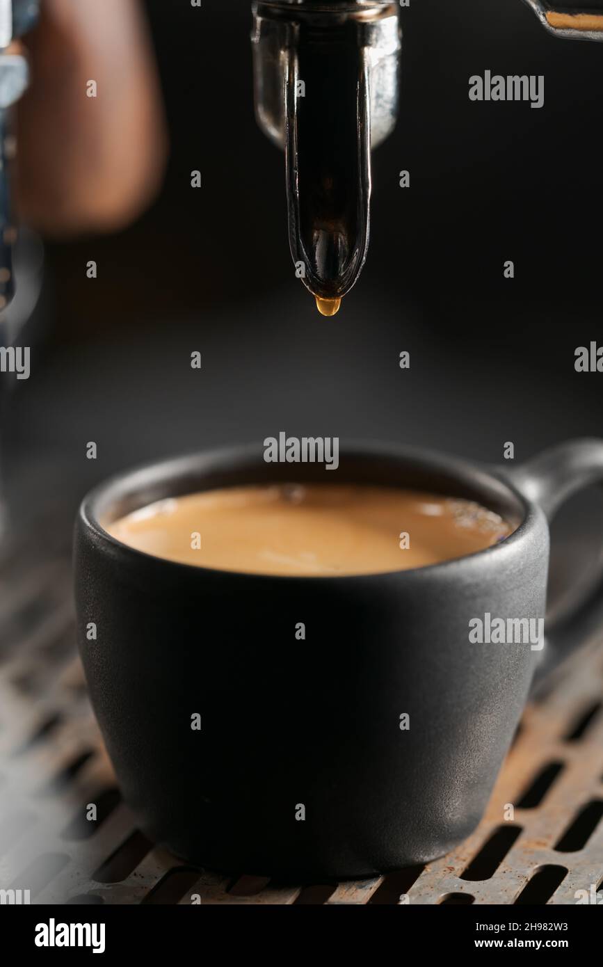 Closeup espresso last drop with single spout portafilter in black cup ...
