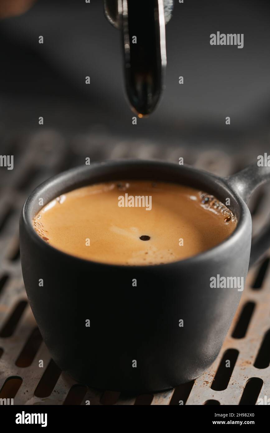 Closeup espresso last drop with single spout portafilter in black cup ...