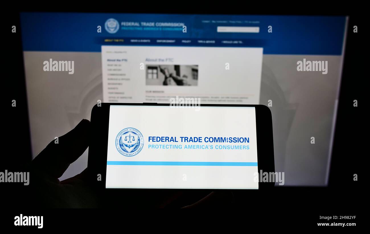 Person holding mobile phone with logo of US government agency Federal ...