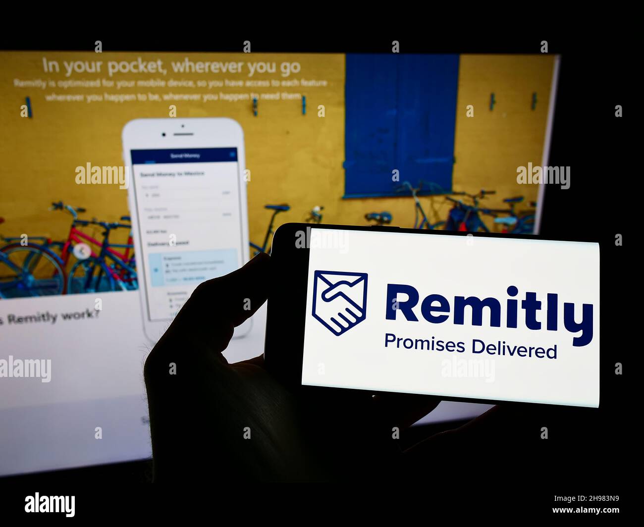 Person holding cellphone with logo of American payment company Remitly ...