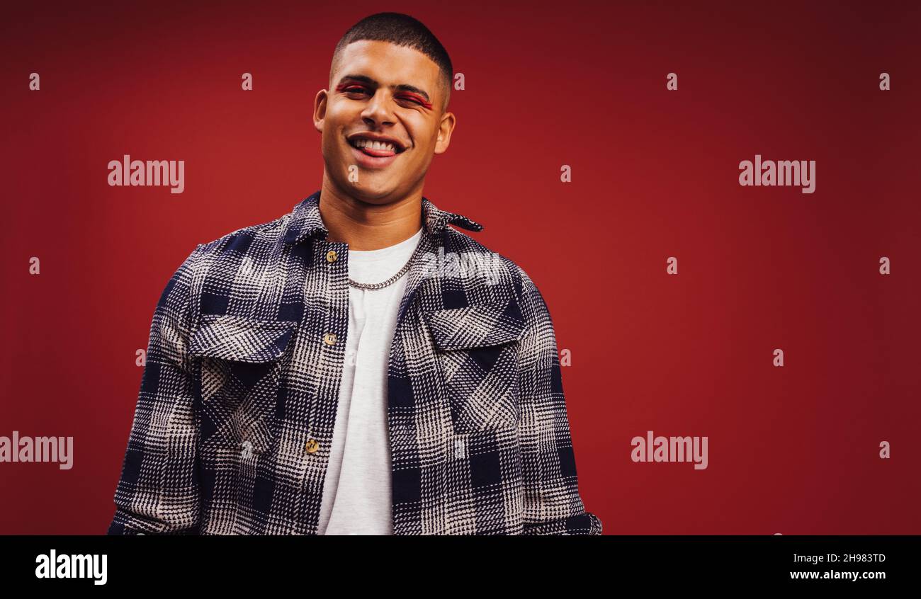 Cheeky young man sticking his tongue out in a studio. Happy young man ...