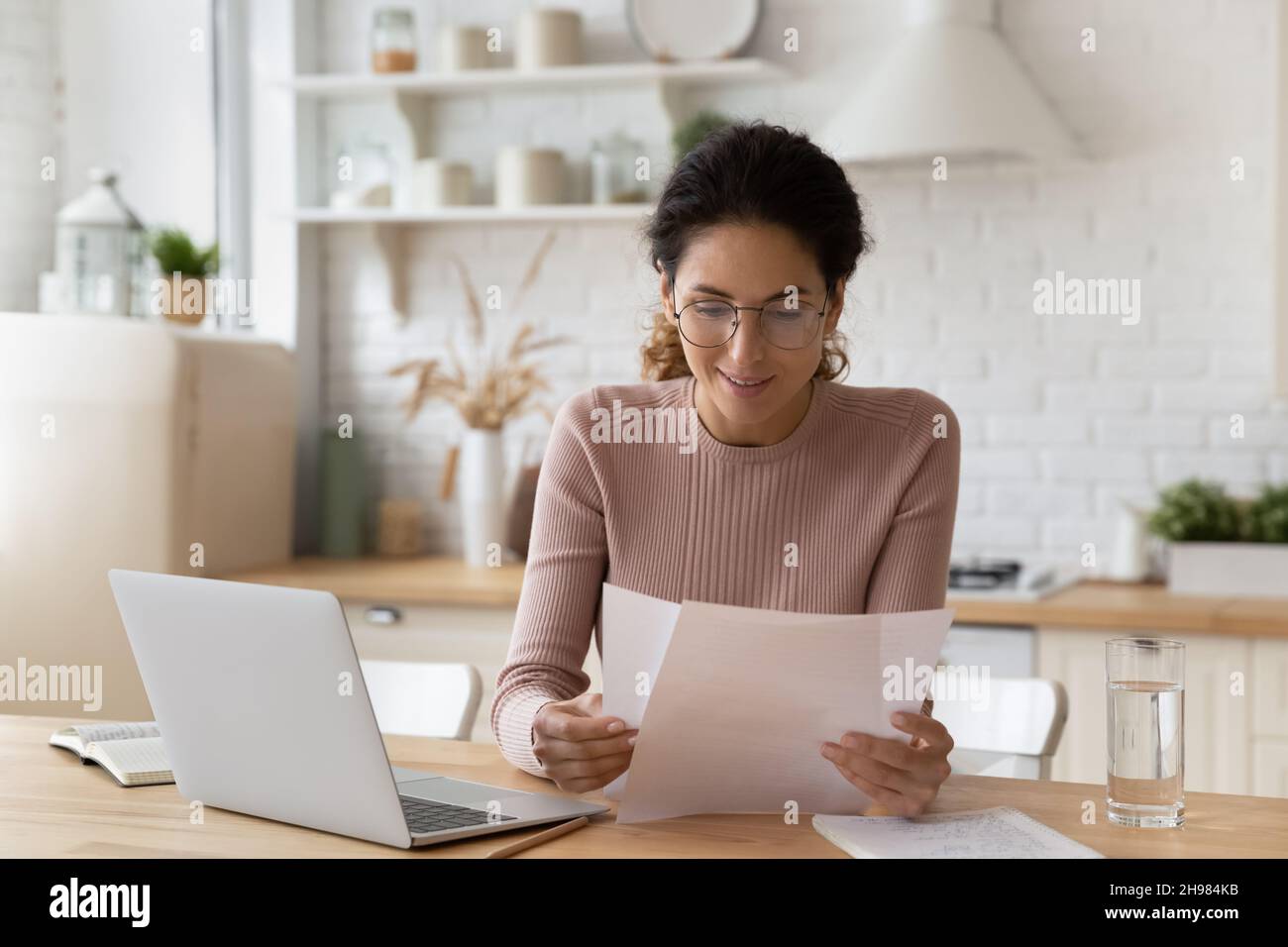 Smiling woman in glasses working with documents, using laptop Stock Photo - Alamy