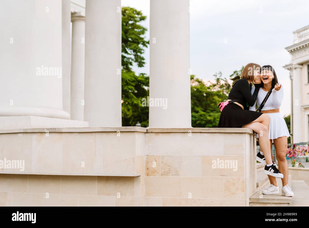 Multiracial two women talking and smiling while walking together ...
