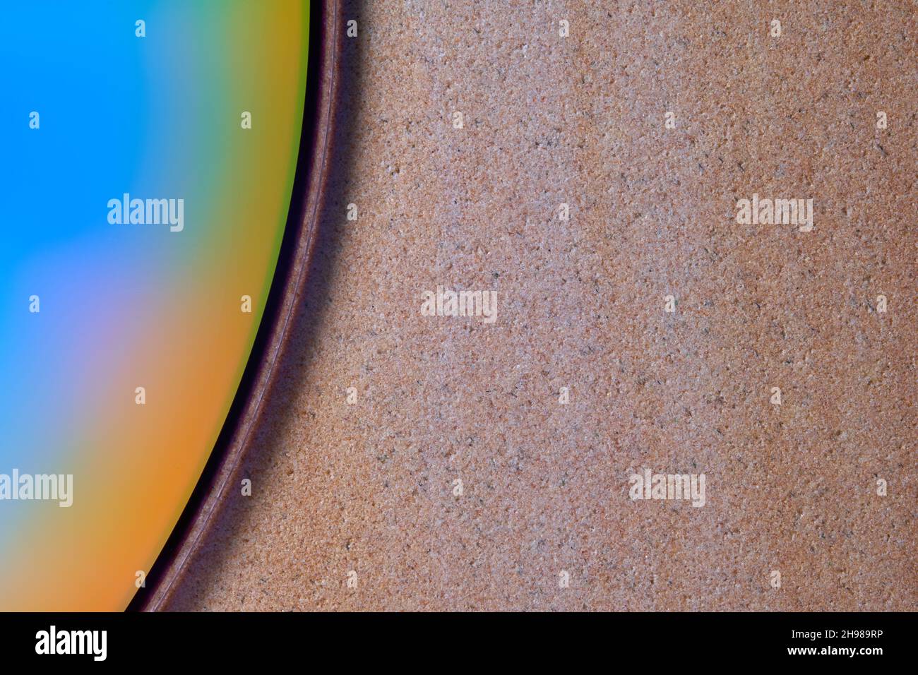 Sandstone background, reflective disk with beautiful colors. Front view ...