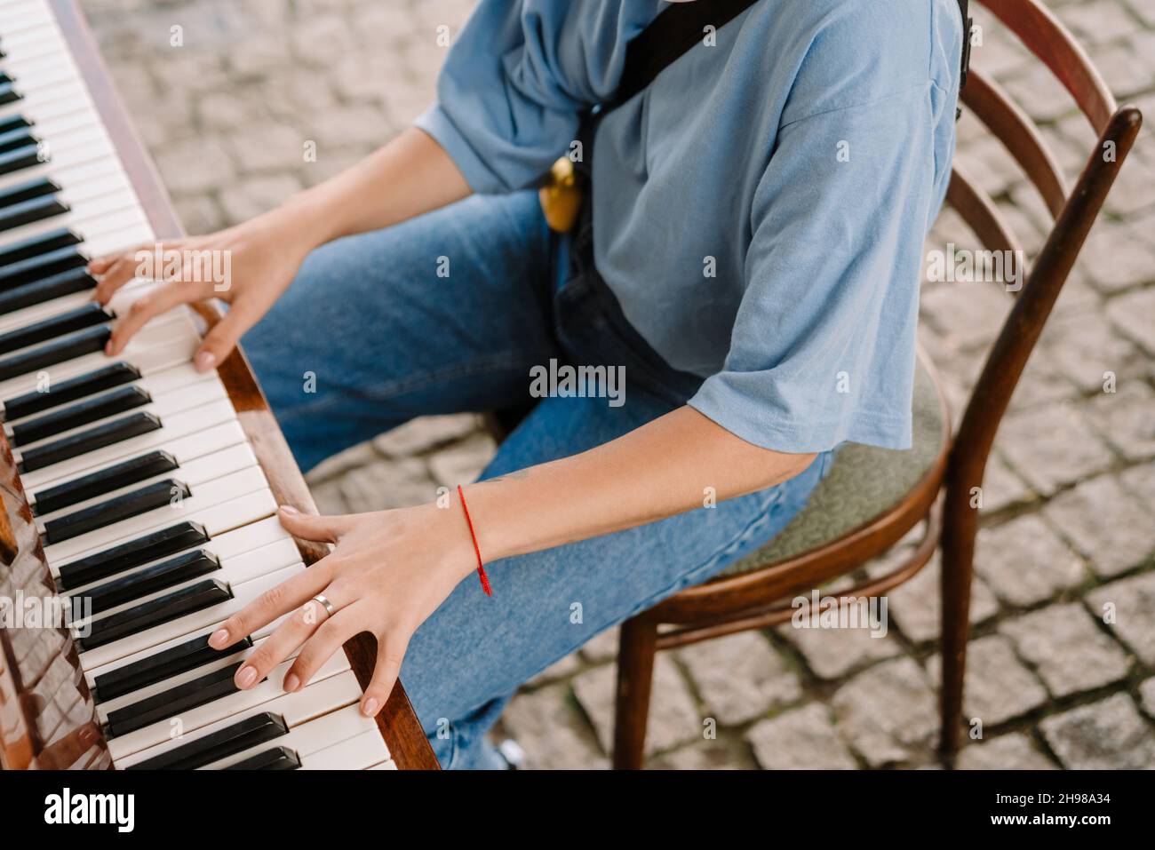 Young woman playing piano while sitting on chair outdoors Stock Photo ...