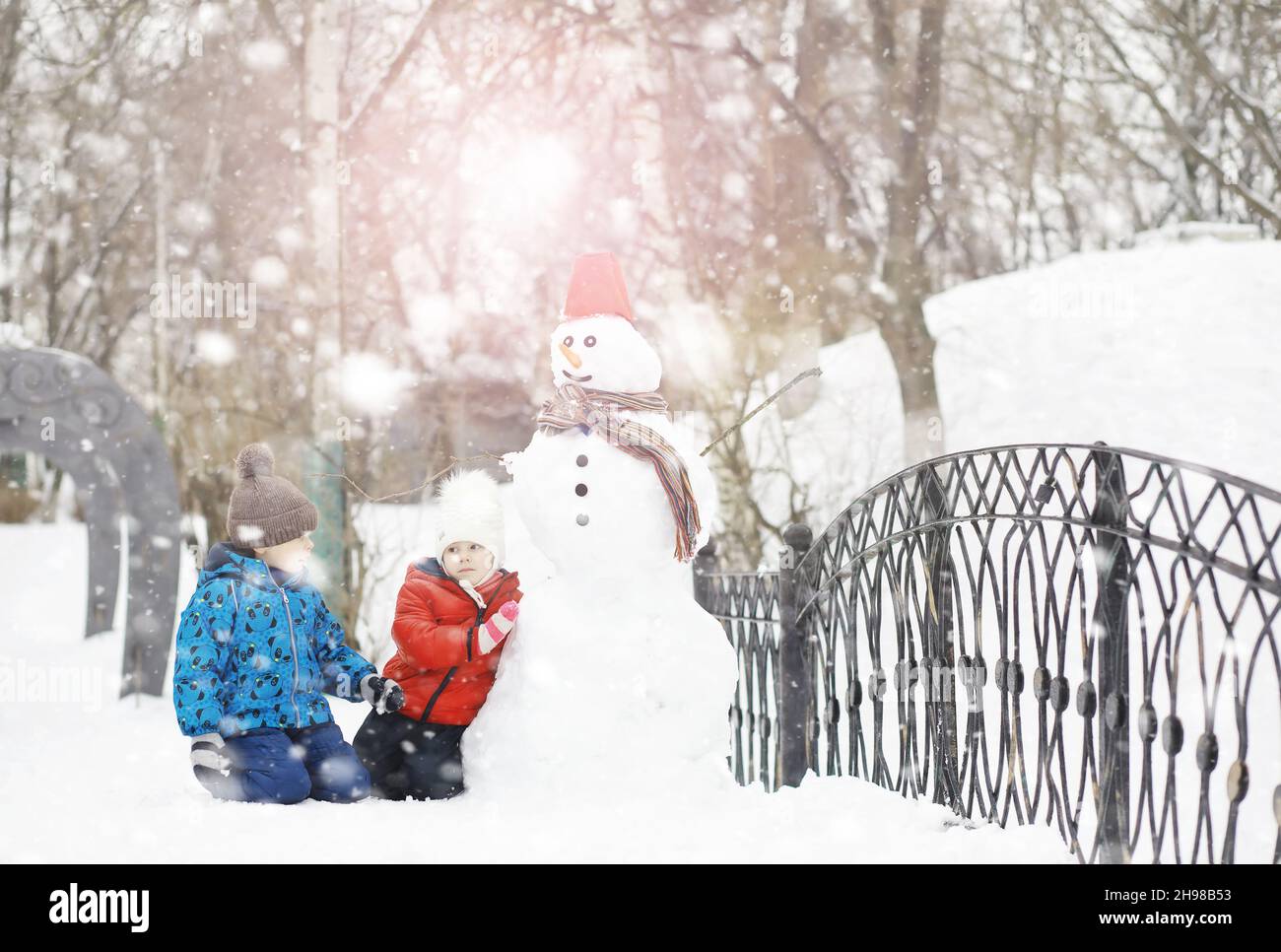 Children in the park in winter. Kids play with snow on the playground ...