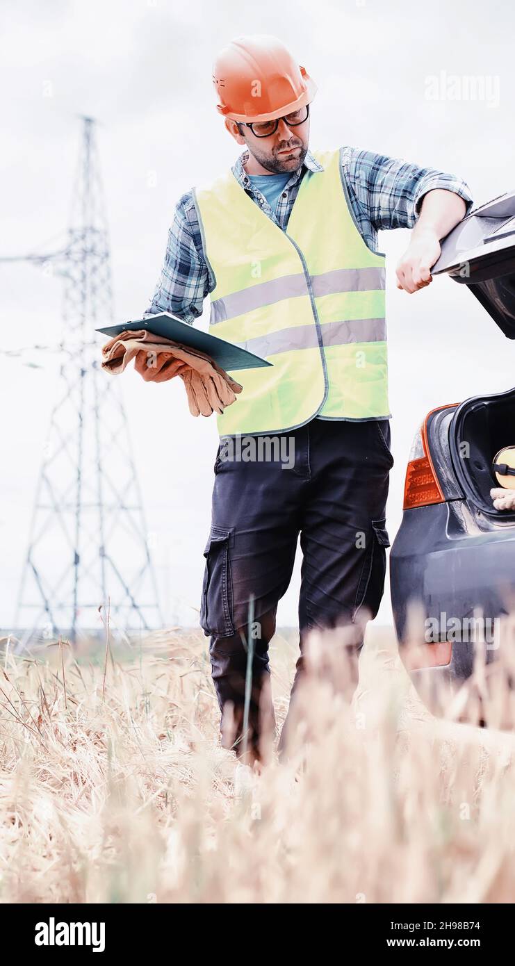 A man in a helmet and uniform, an electrician in the field ...