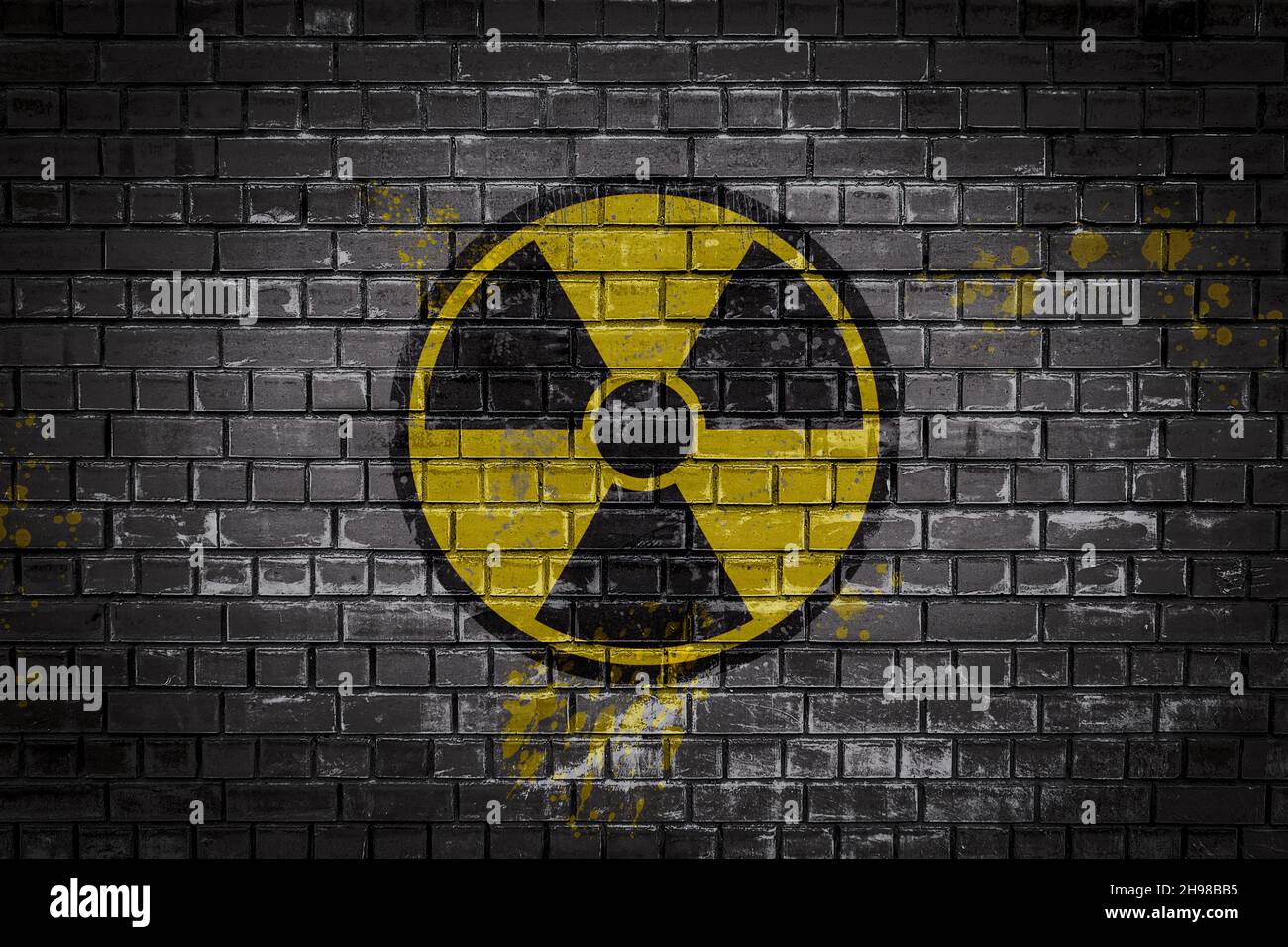 A shabby radiation sign depicted on a dark brick wall warning of ...
