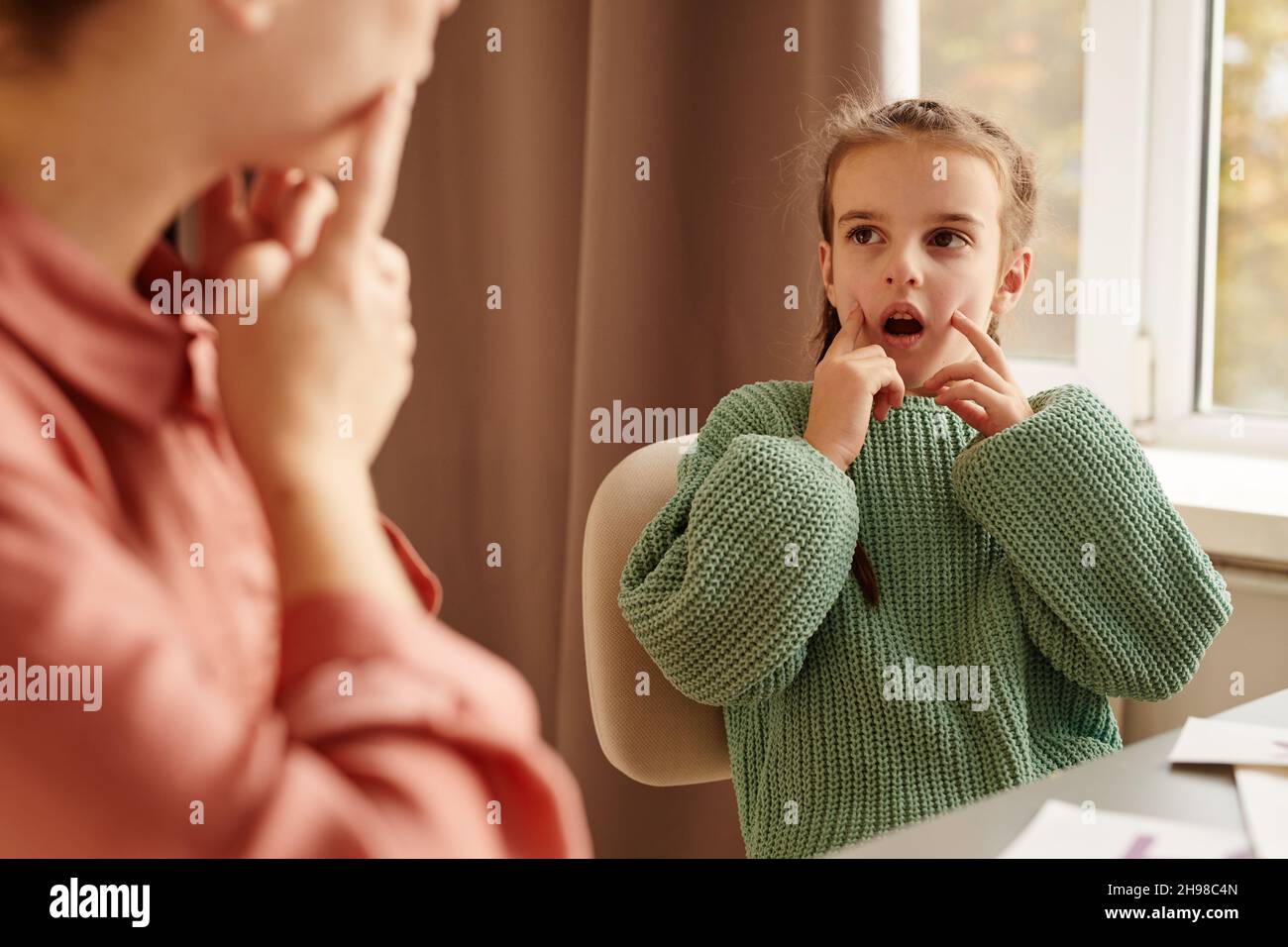 Little girl repeating for her teacher at the table, she learning to ...