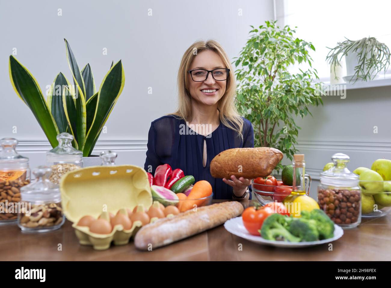 Woman with bread in her hands, with food on the table, looking at the ...