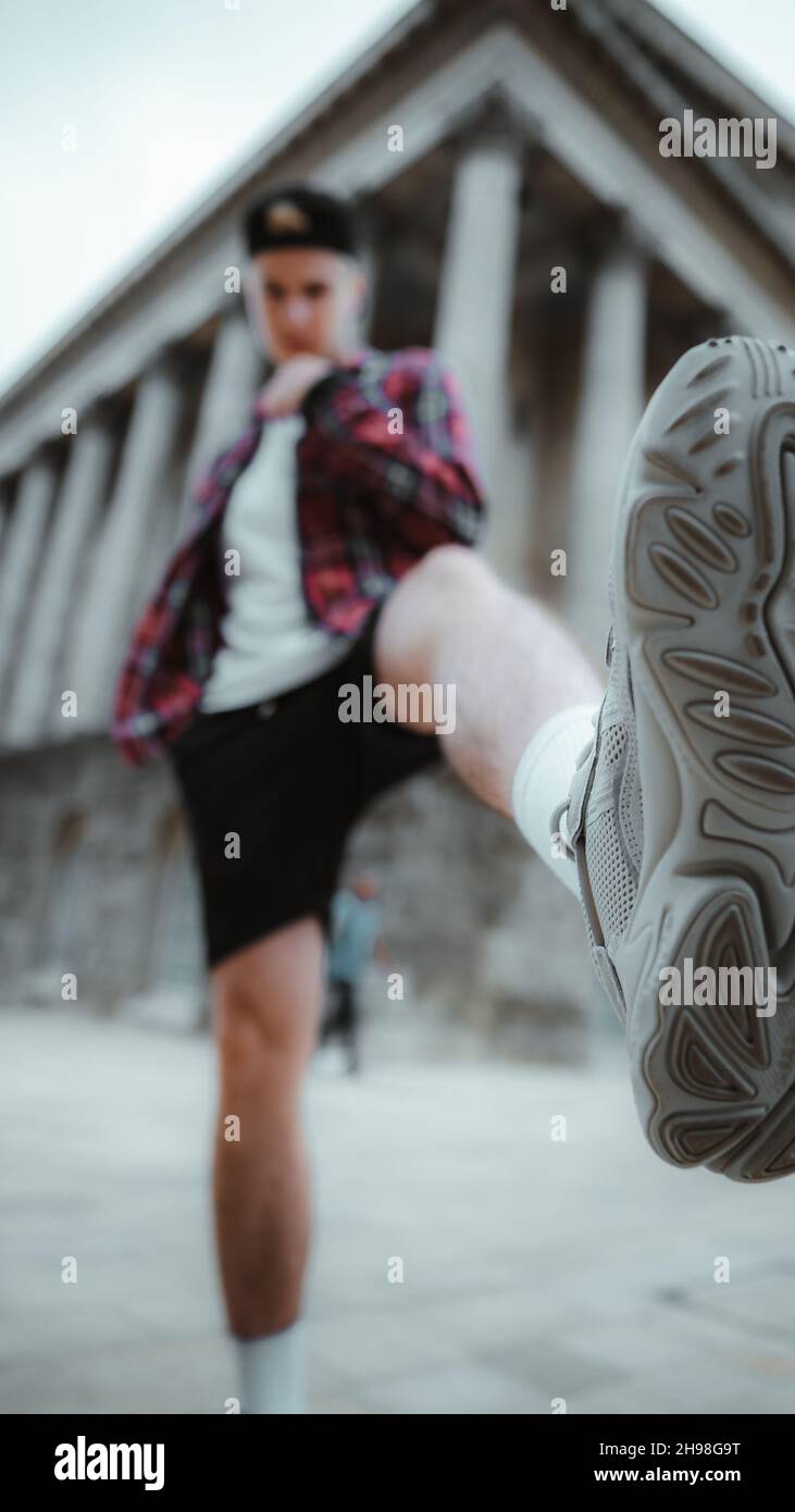 A confident young man stepping on a camera with a Roman-style building ...