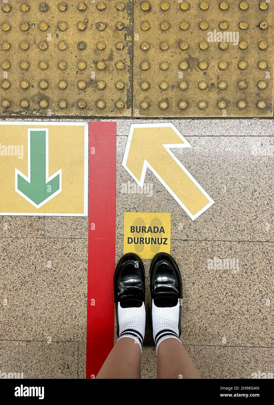 A vertical shot of a person's feet near the Stop here sign Stock Photo ...