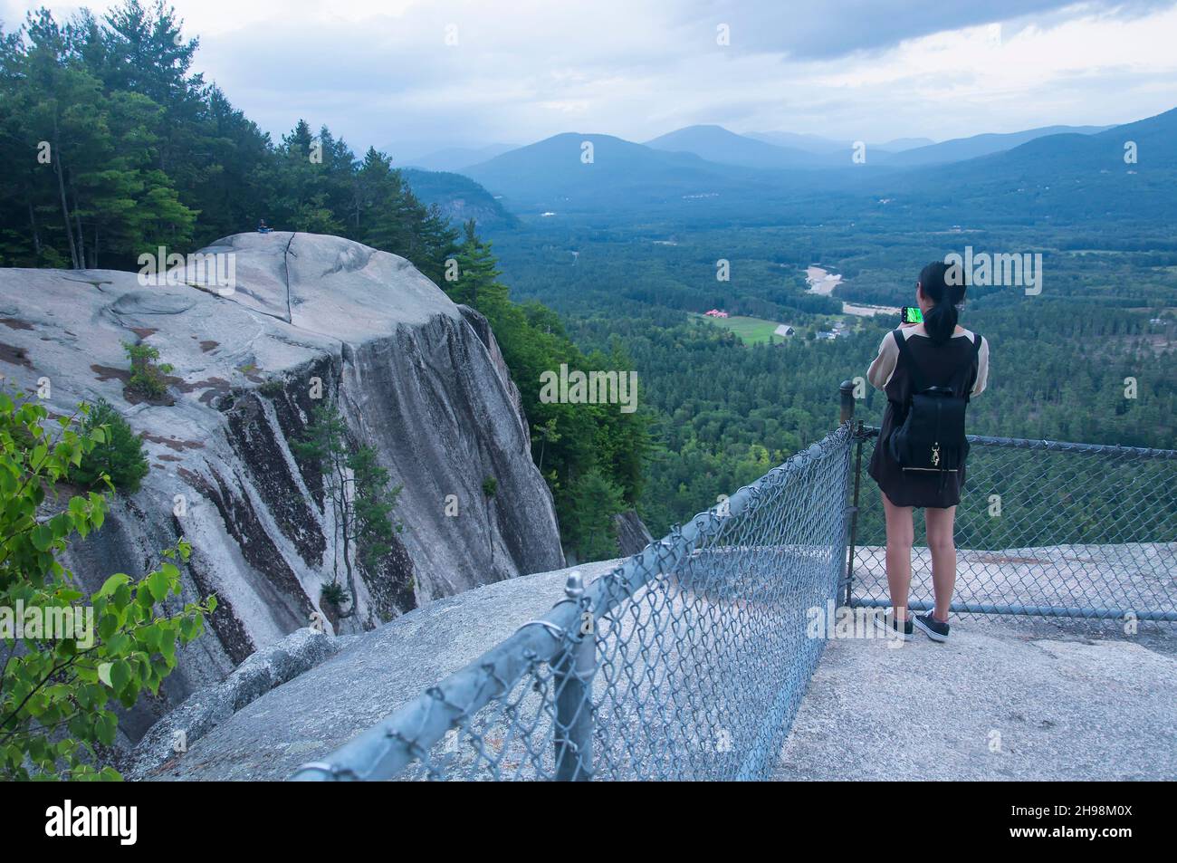 a woman taking pictures of mount washington valley from on top of ...