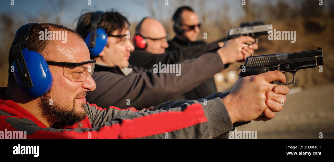 Group of people practice gun shoot on target on outdoor shooting range ...